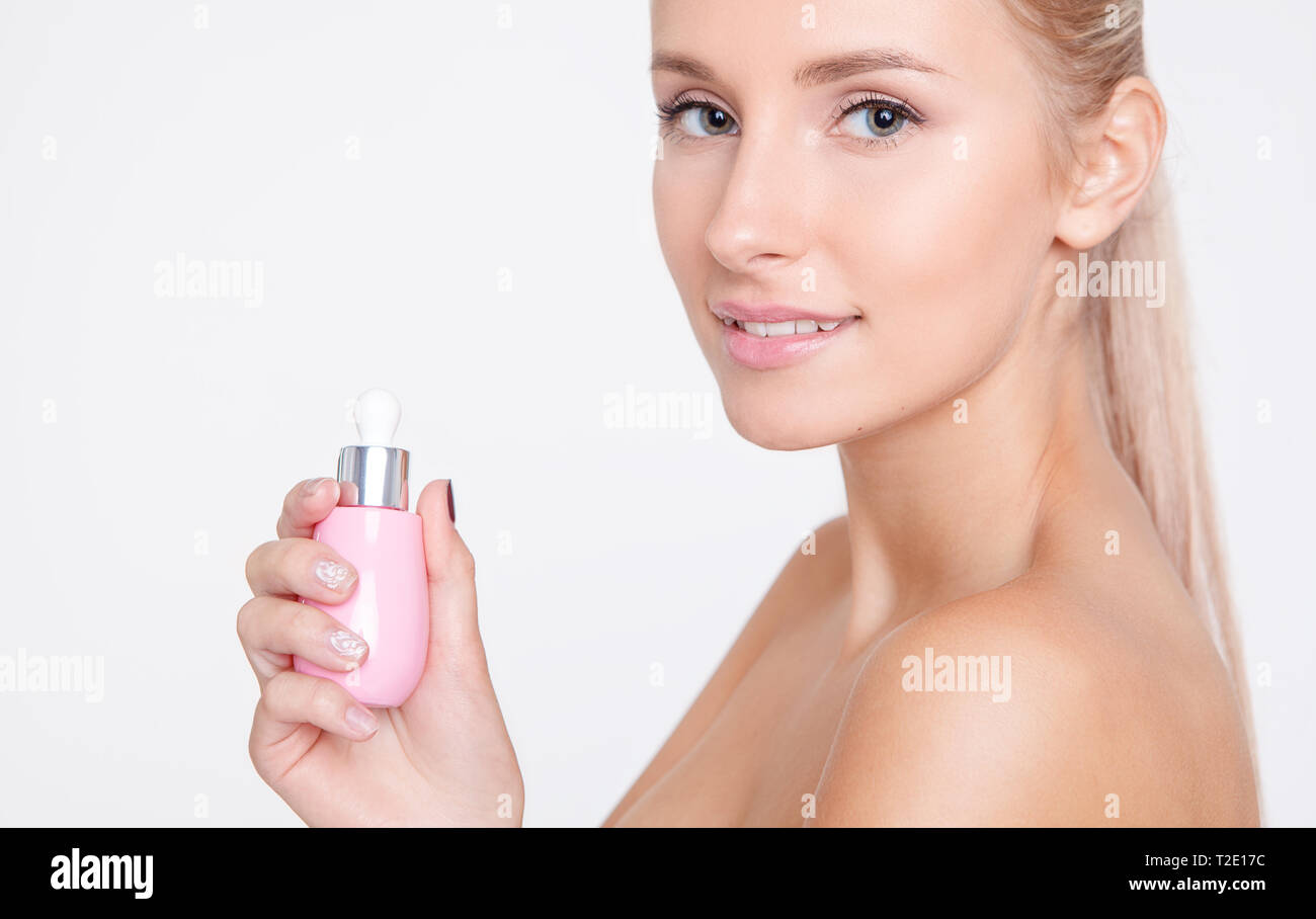 beautiful model applying a skin serum treatment on grey background ...