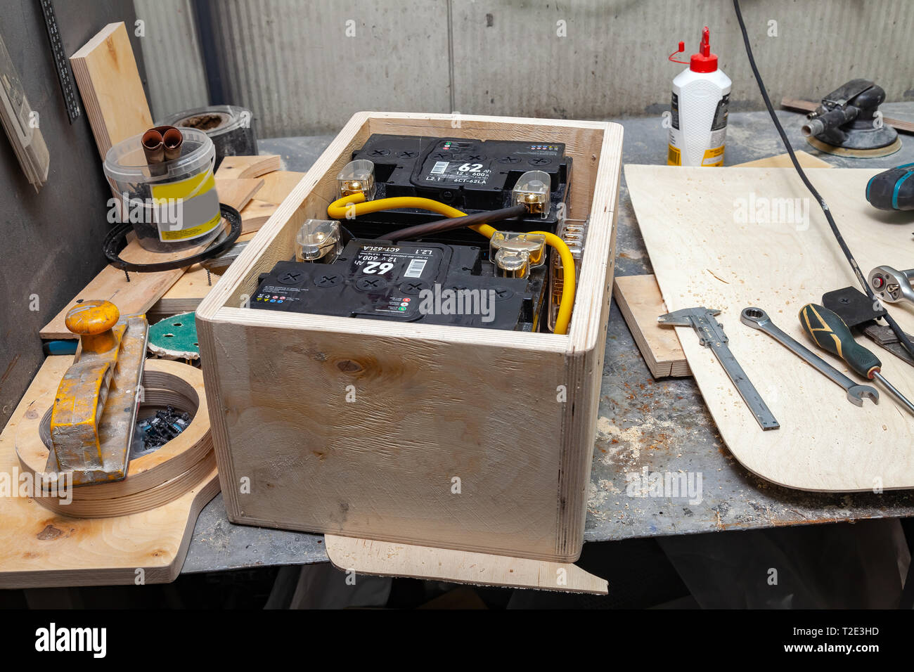 Wooden box with two car batteries connected together on a workbench ...