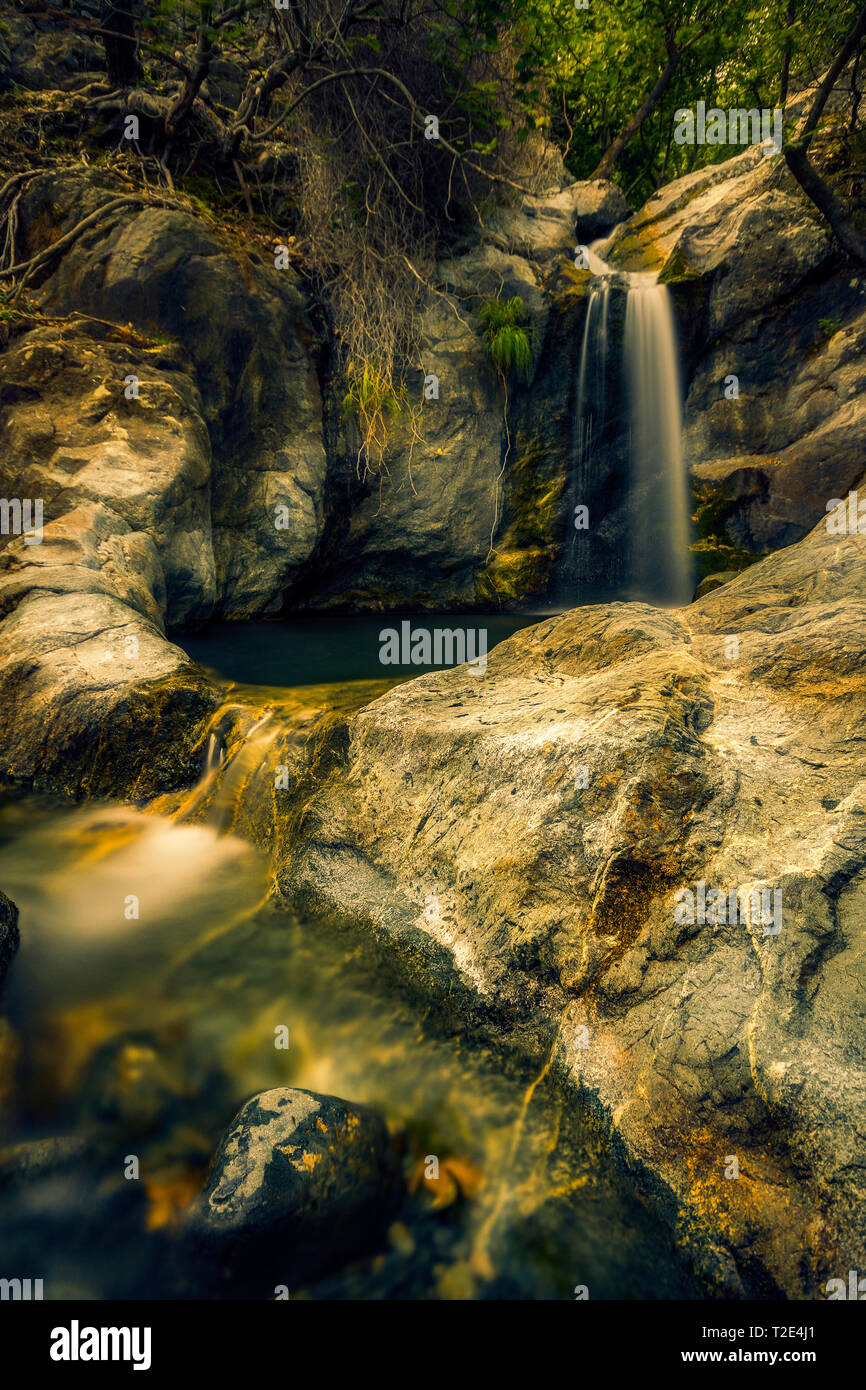 Small and beautiful waterfall forming a deep water hole surrounded by ...