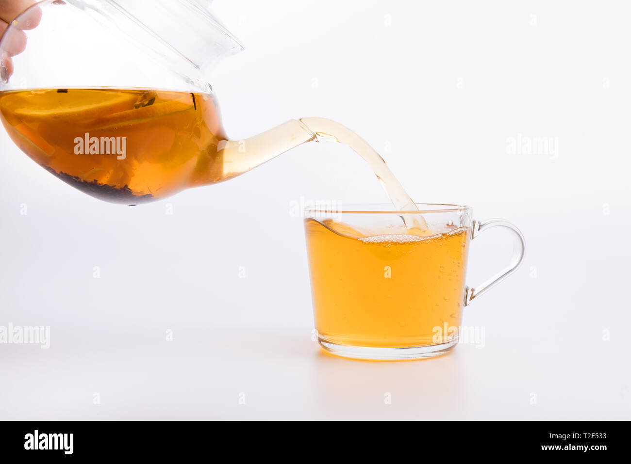 Glass teapot pouring green tea into cup isolated on white background ...