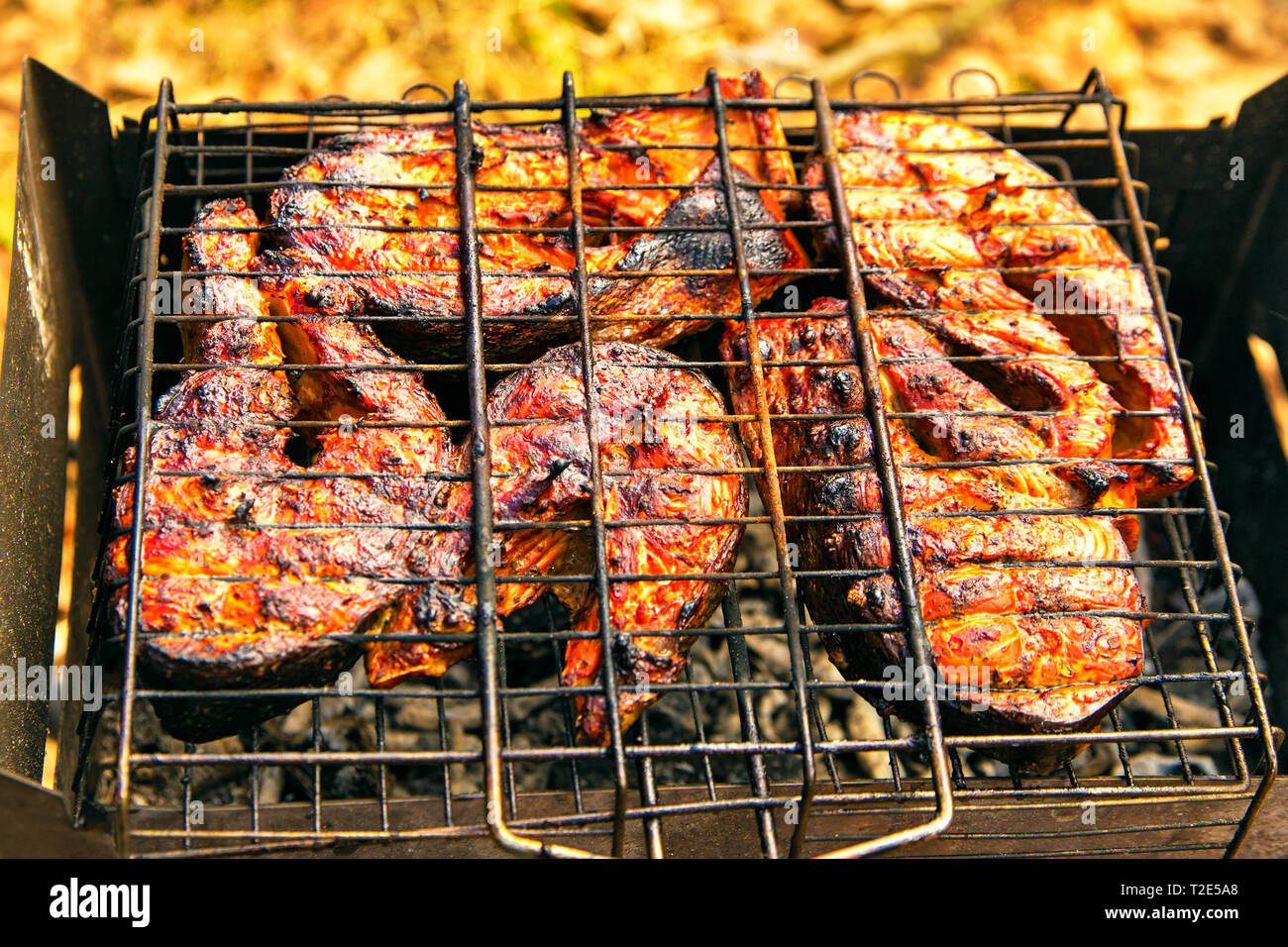grilling salmon steak with ginger marinade in wire rack over barbecue ...