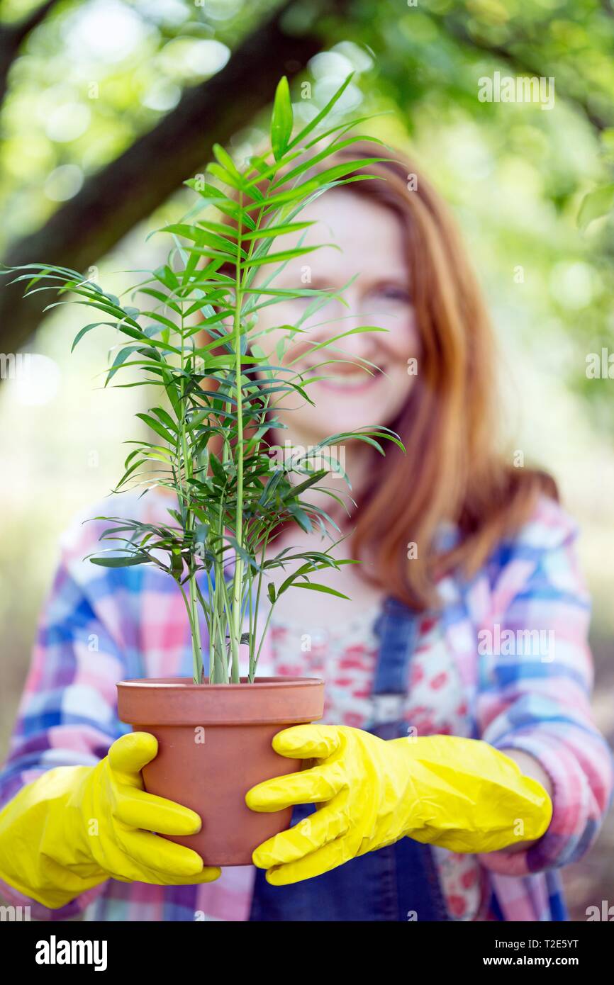 smiling girl plants a flowers in the garden. flower pots and plants for ...