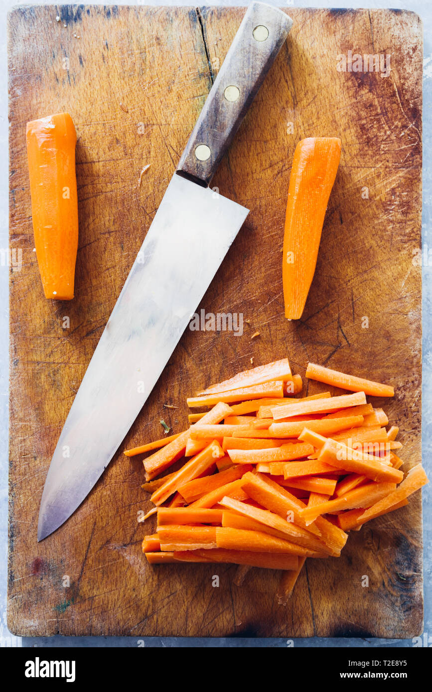 Carrot sticks, cut on a cutboard with a big knfe, ready to be prepared ...