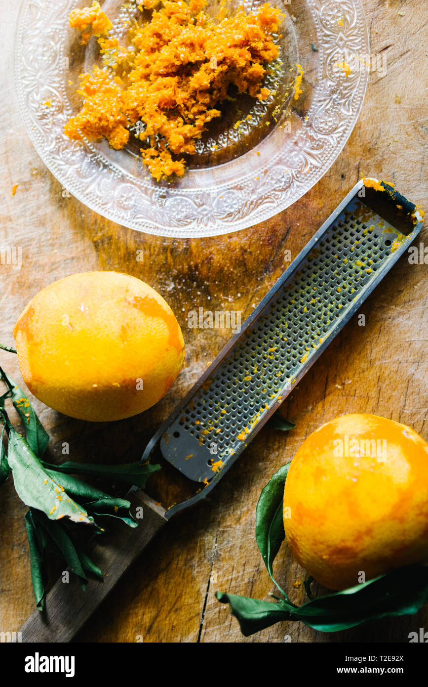 Orange zest, grating ornage zest from fresh fruit, top view with a zest ...