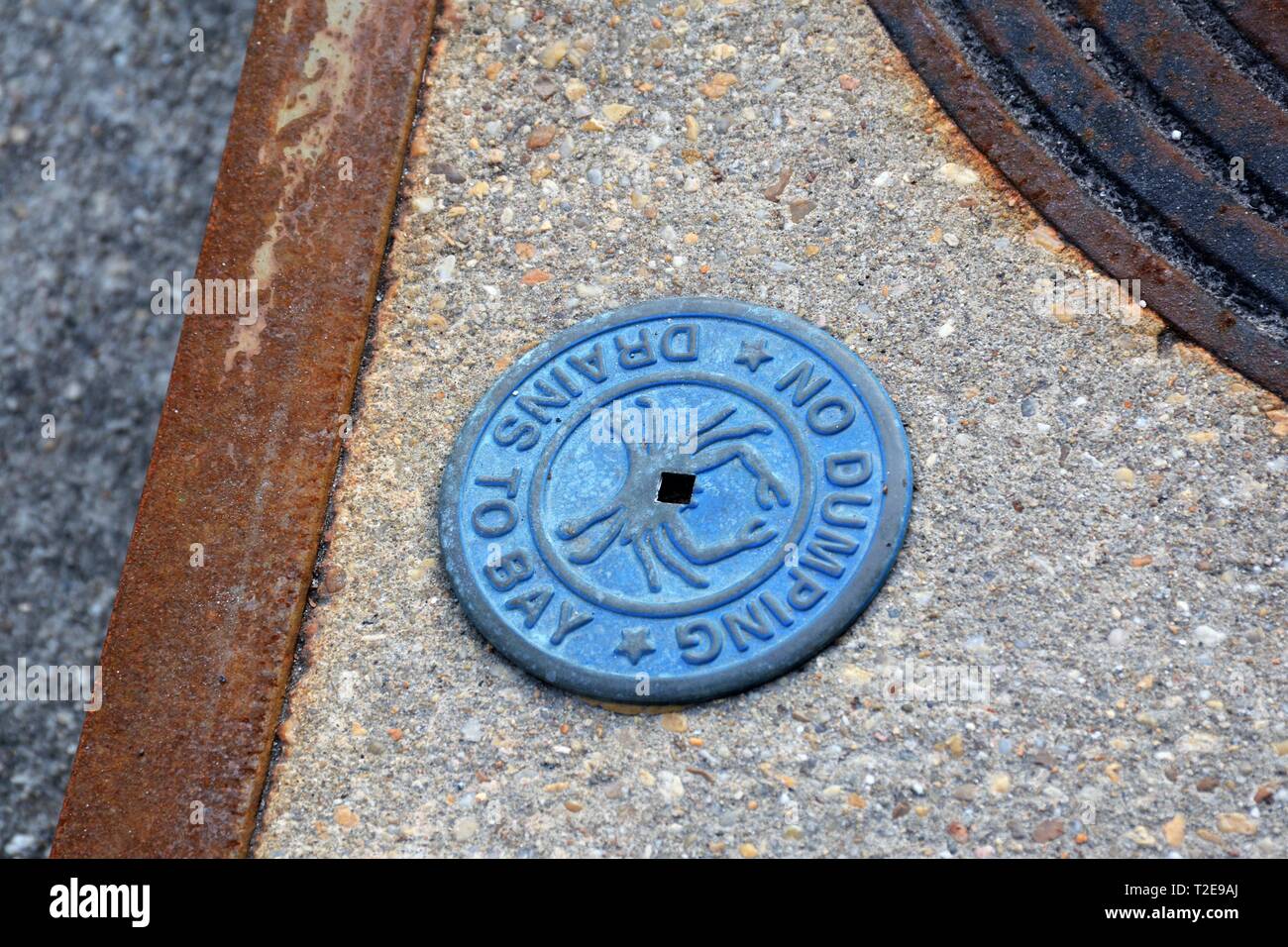 sign next to drain cover which leads from street to the ocean, the ...