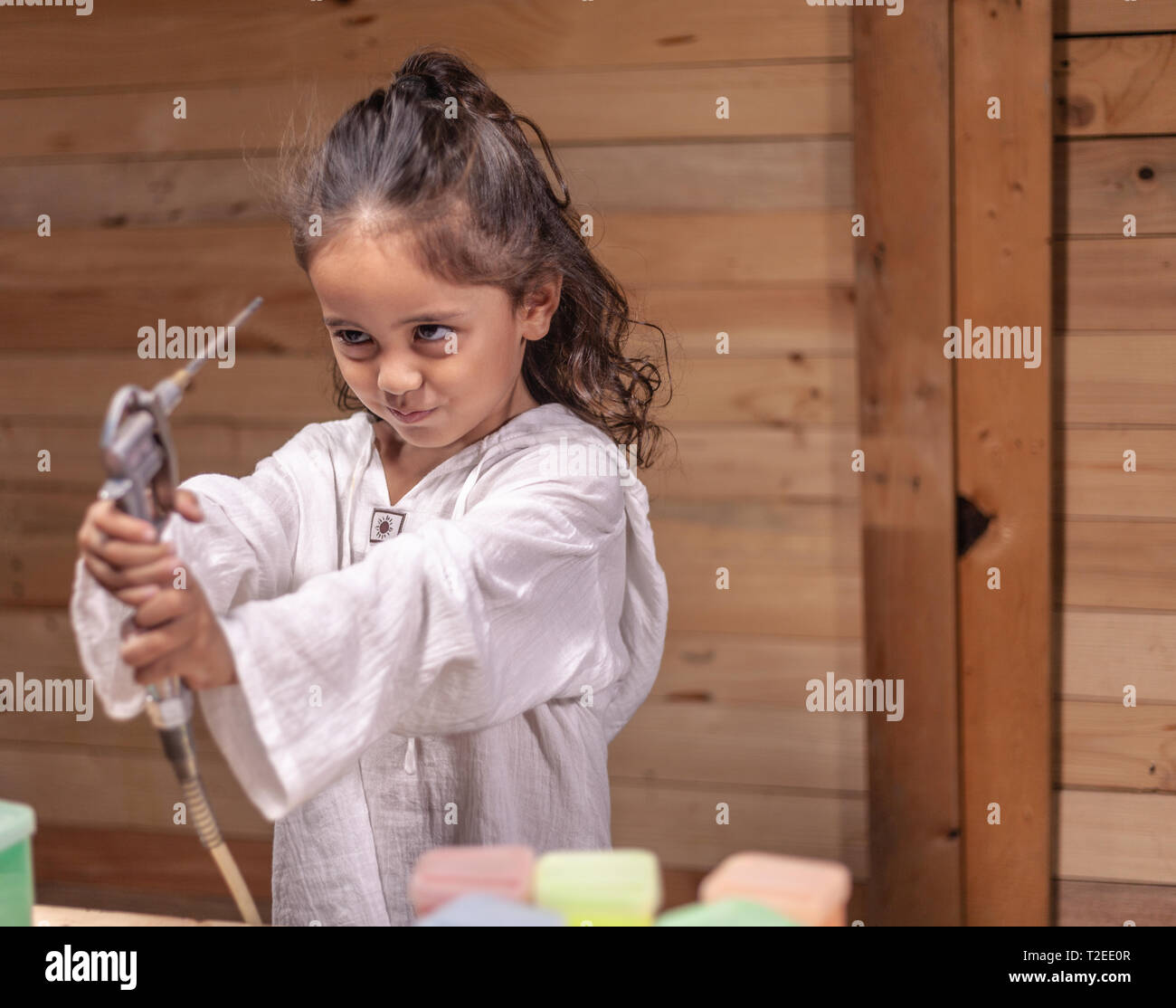 A long haired boy blowing his hair with air compressor in wooden room ...