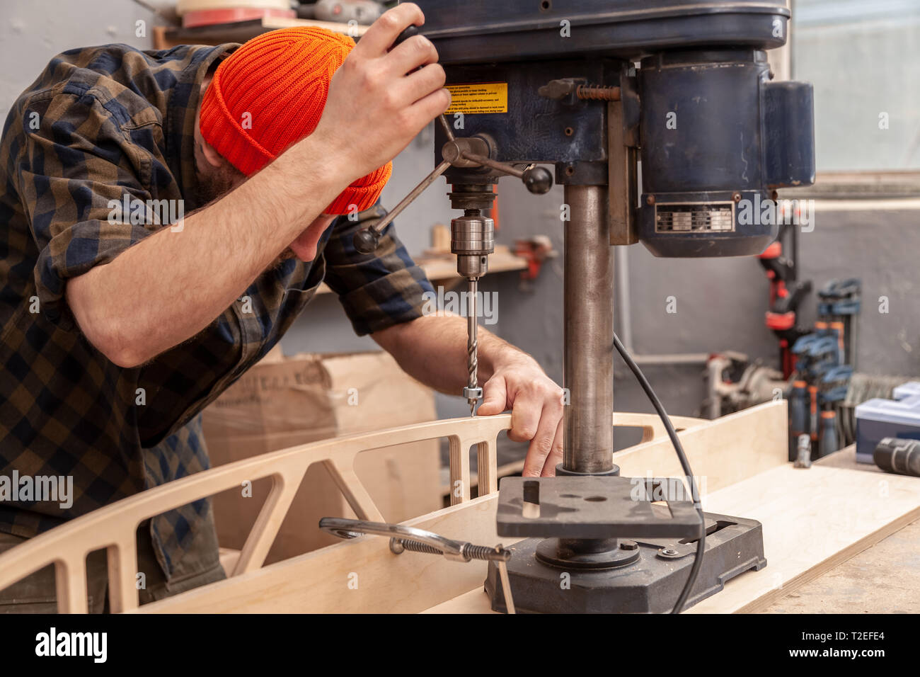 Carpenter drills a hole with an electrical drill in wooden board. Wood ...
