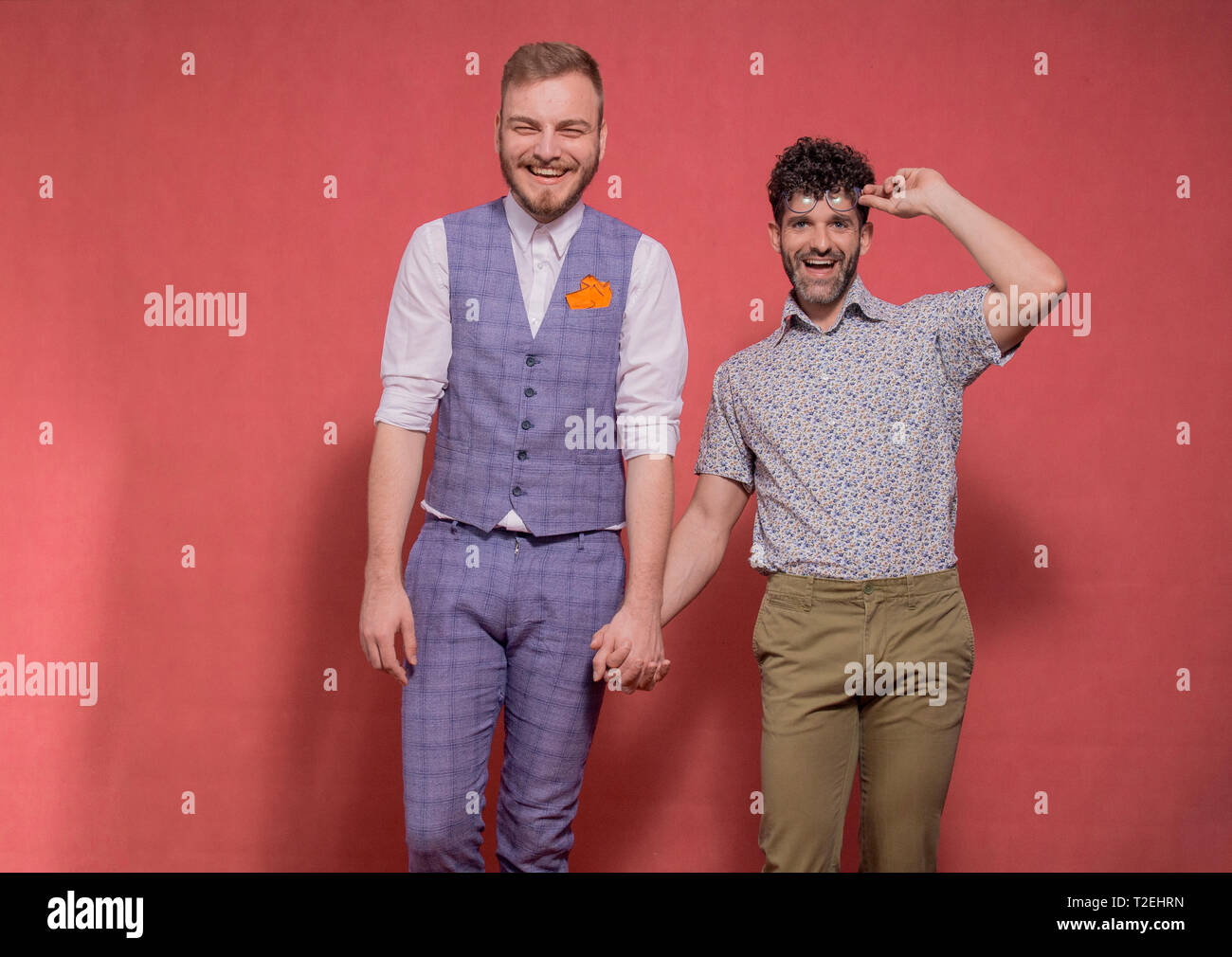 two men, smiling and happy gay couple holding hands together, shot in ...