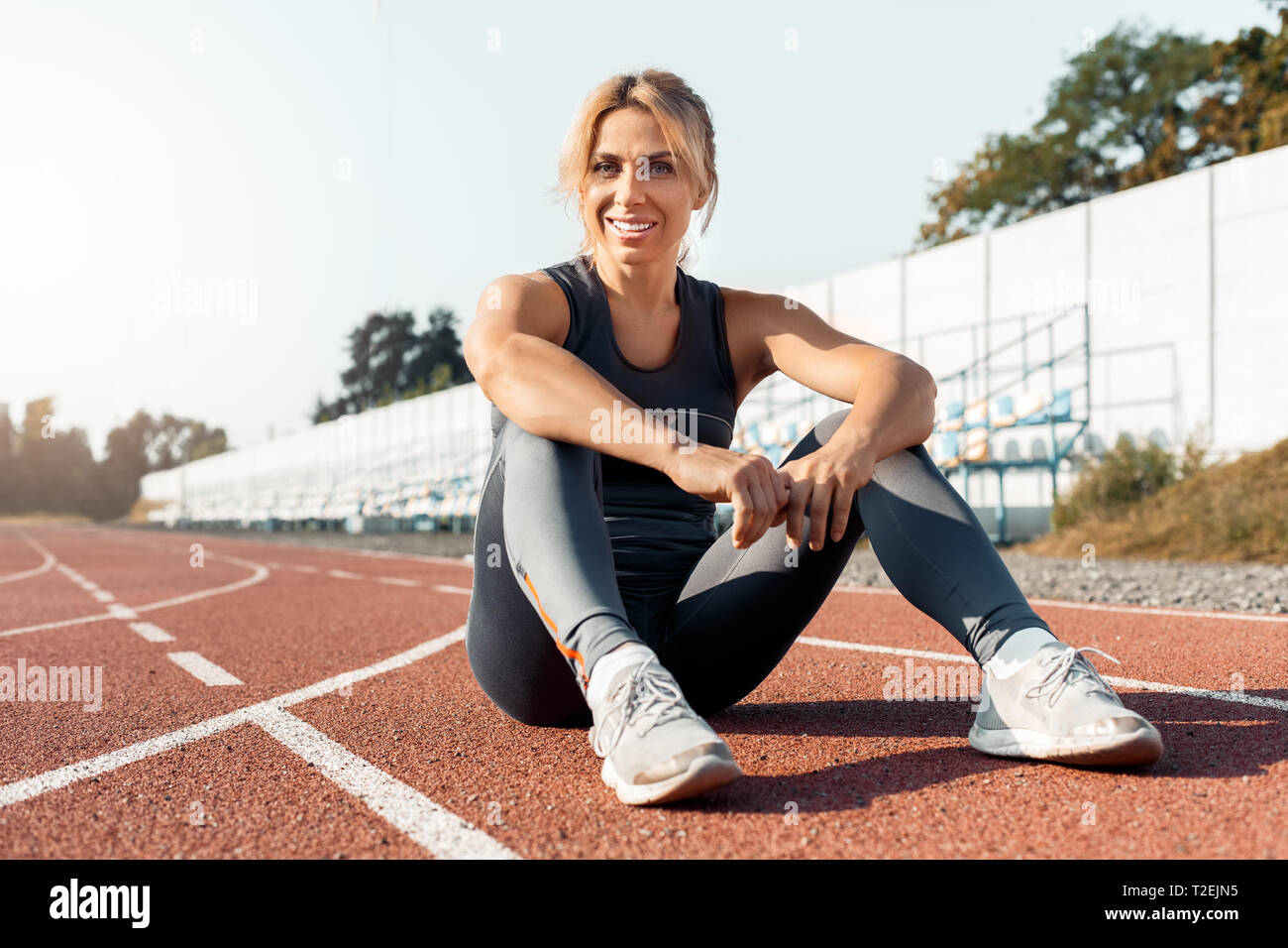 Young woman athlete on stadium sporty lifestyle sitting on track ...