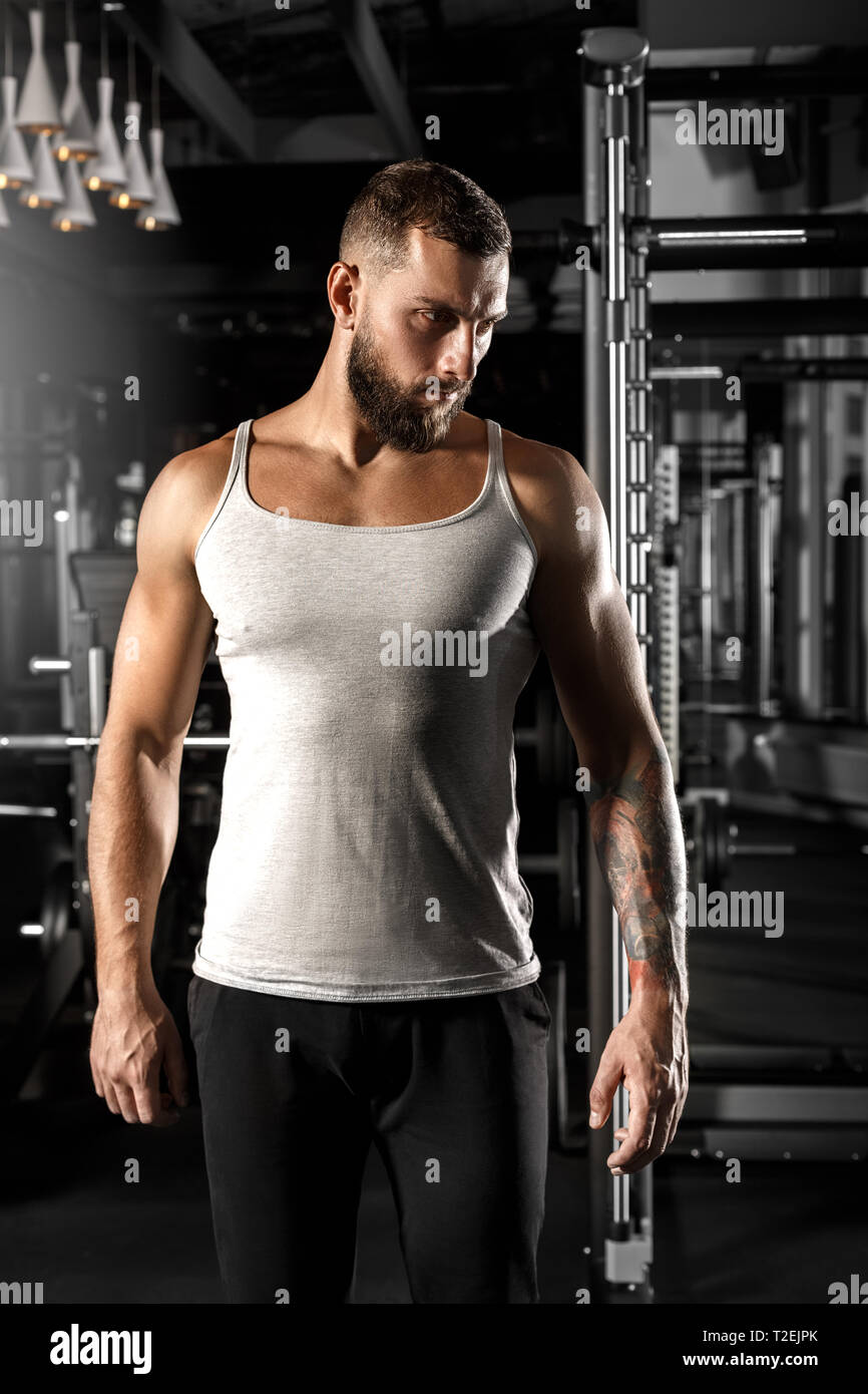 Bearded man bodybuilder standing at gym looking aside thoughtful Stock ...
