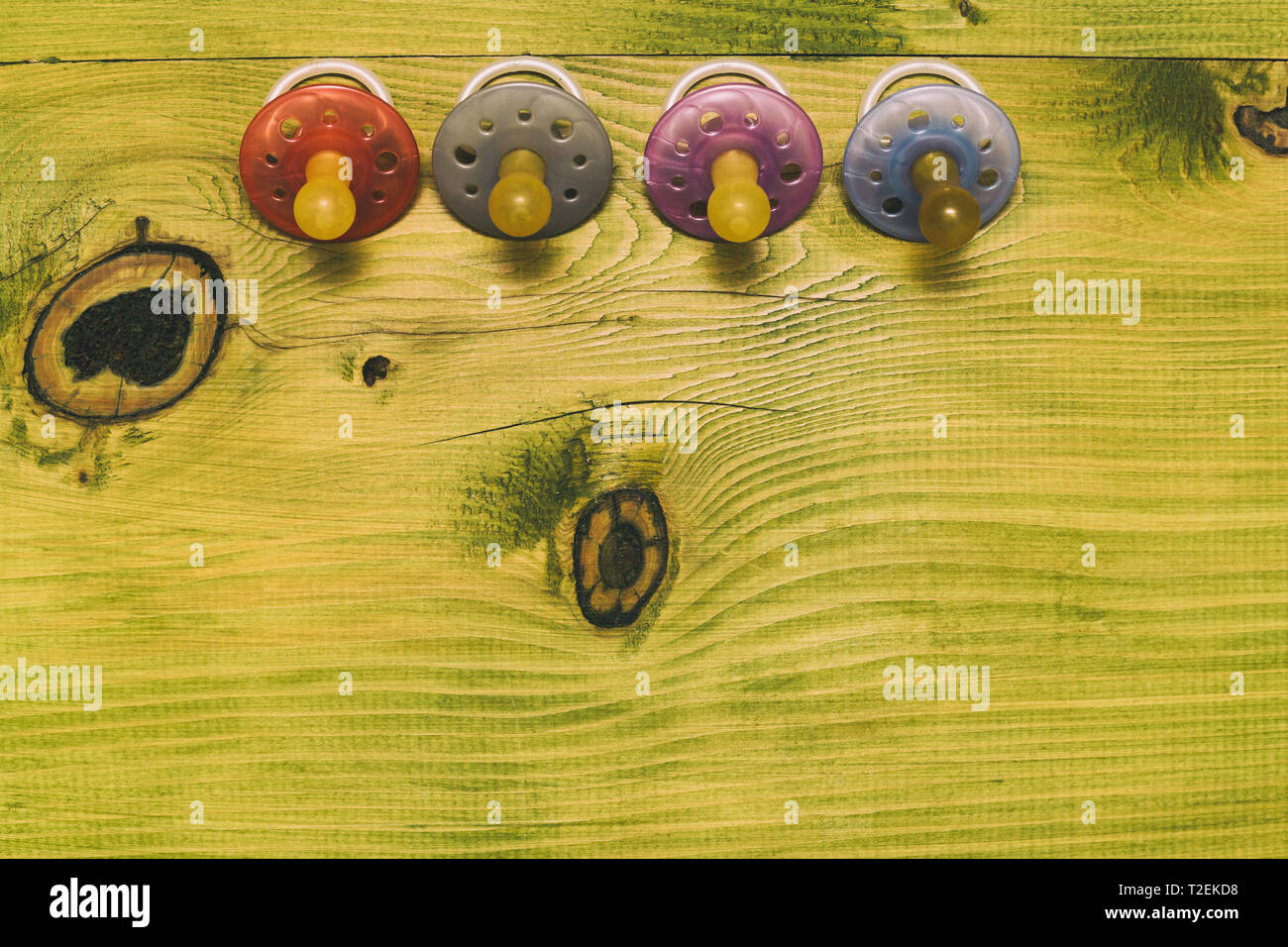 Pacifier with different color for baby boy and girl on wooden table ...