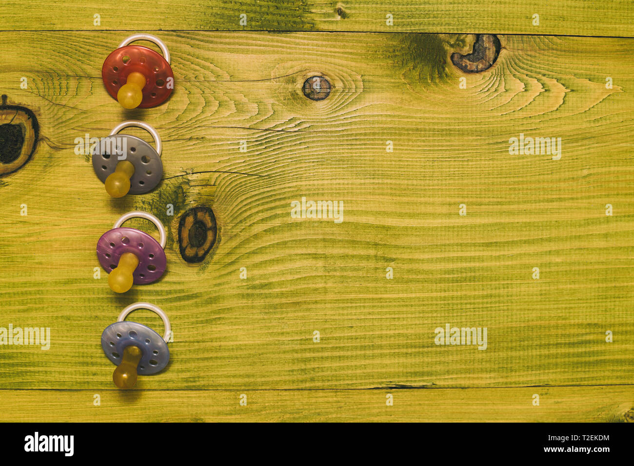 Pacifier with different color for baby boy and girl on wooden table ...