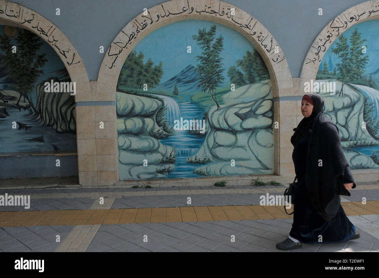 A Bedouin woman walks past a painted wall in Rahat a predominantly ...