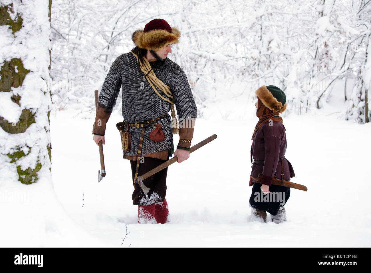 Father and son Vikings in a deep winter forest and the father teaches ...