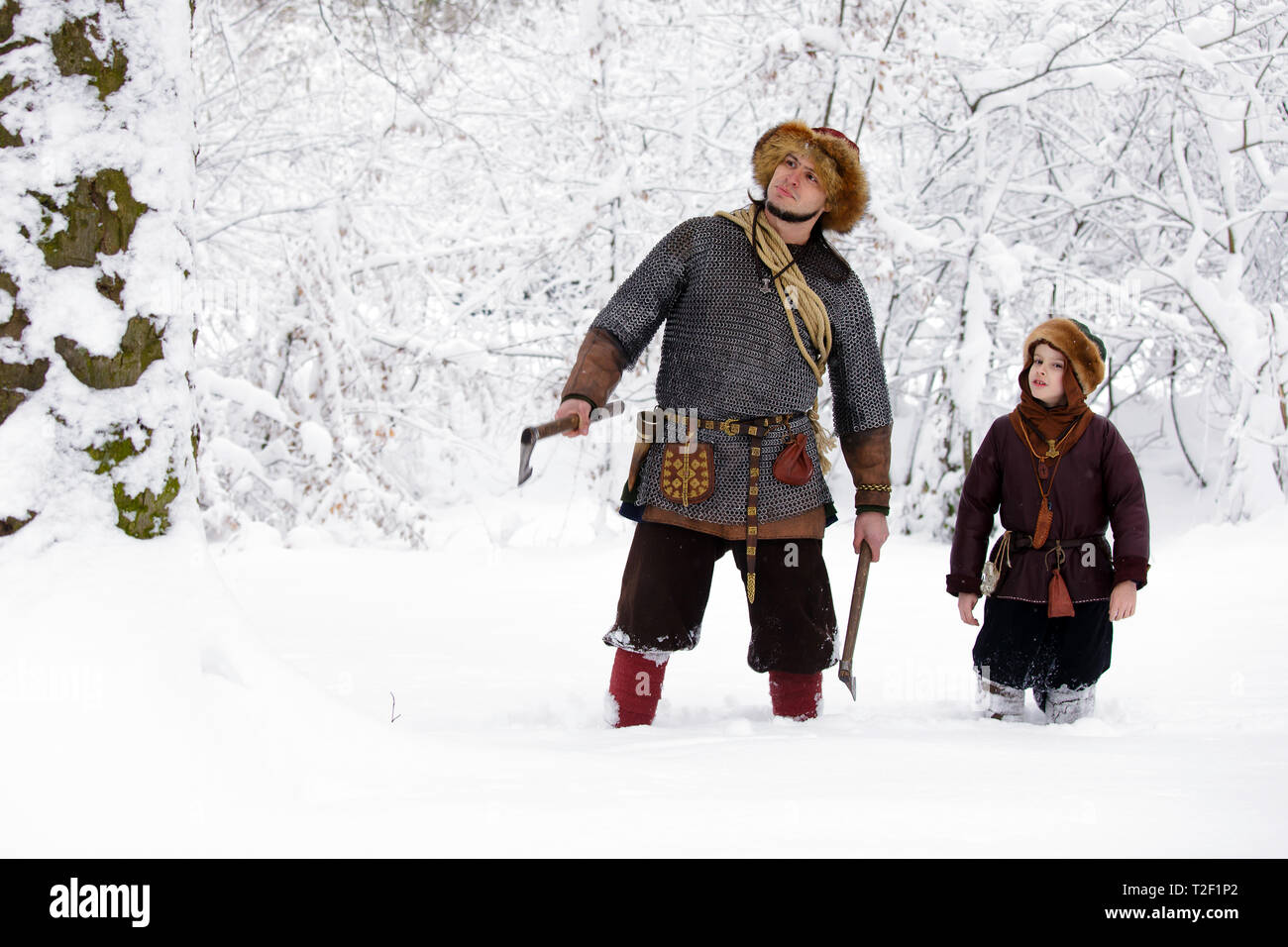 Father and son Vikings in a deep winter forest and the father teaches ...