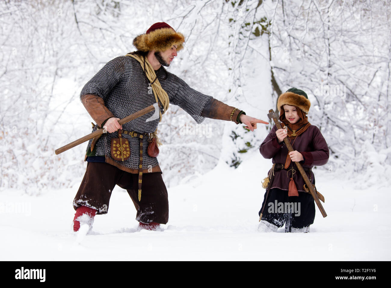Father and son Vikings in a deep winter forest and the father teaches ...