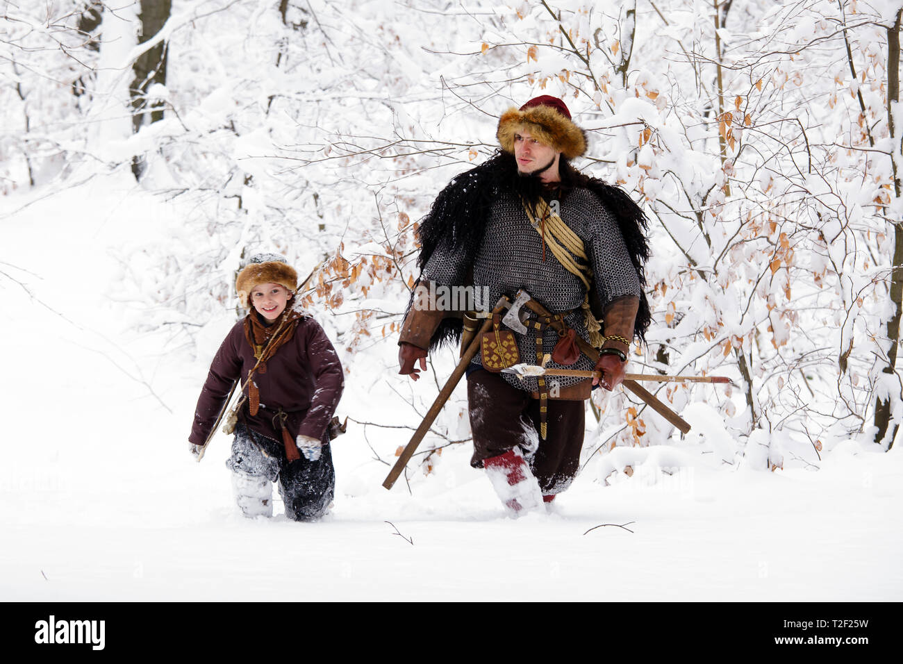 Father and son Vikings in a deep winter forest and the father teaches ...