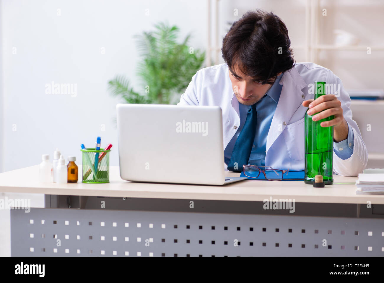 Young male doctor drinking in the office Stock Photo - Alamy
