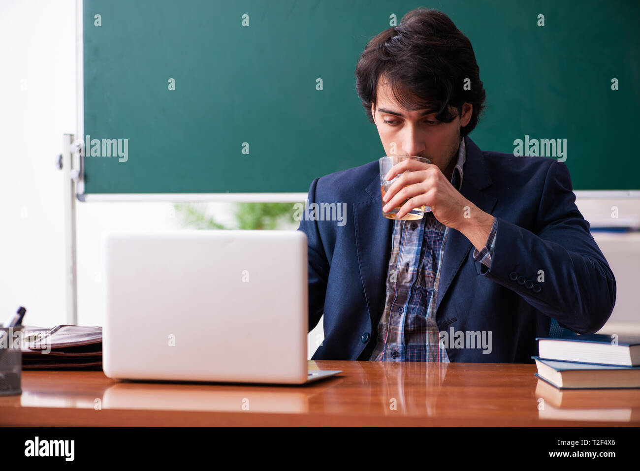 Male teacher drinking in the classroom Stock Photo - Alamy
