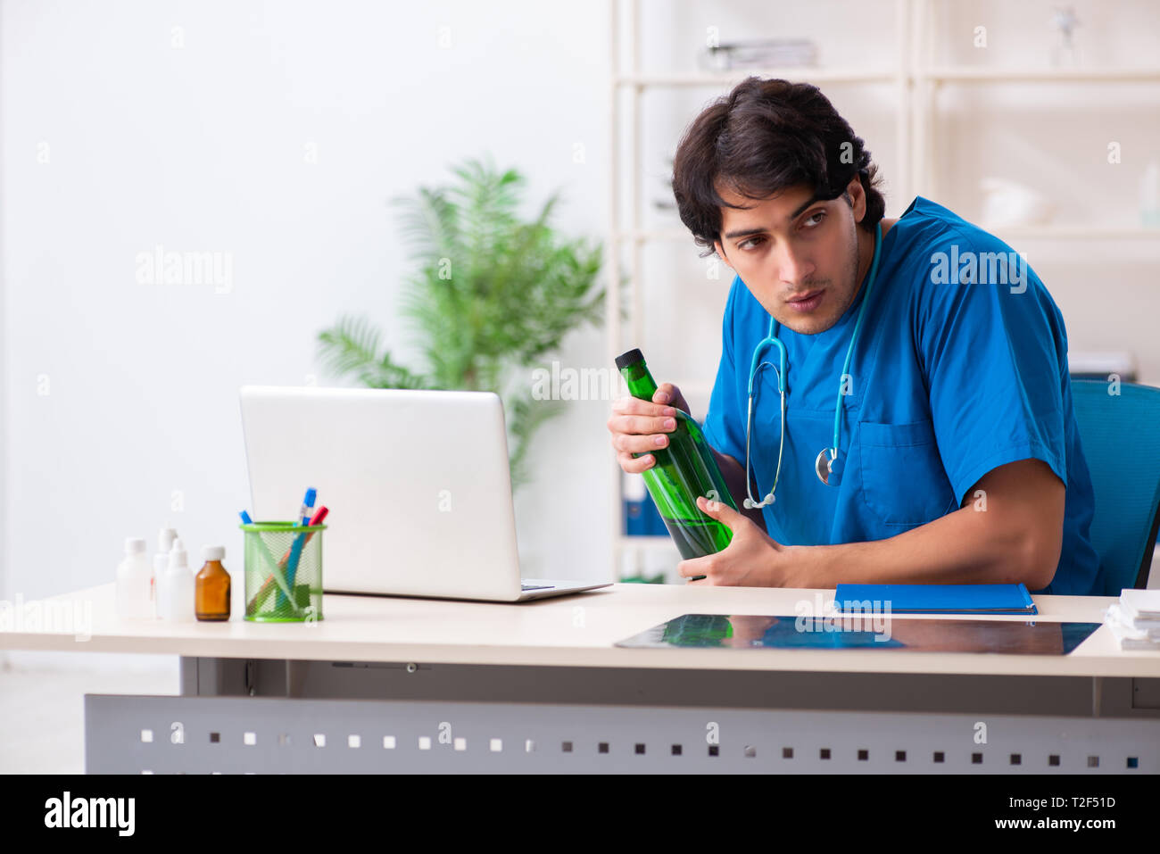 Young male doctor drinking in the office Stock Photo - Alamy
