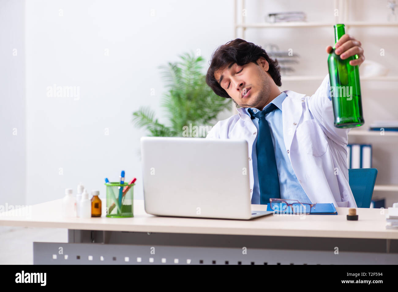 Young male doctor drinking in the office Stock Photo - Alamy