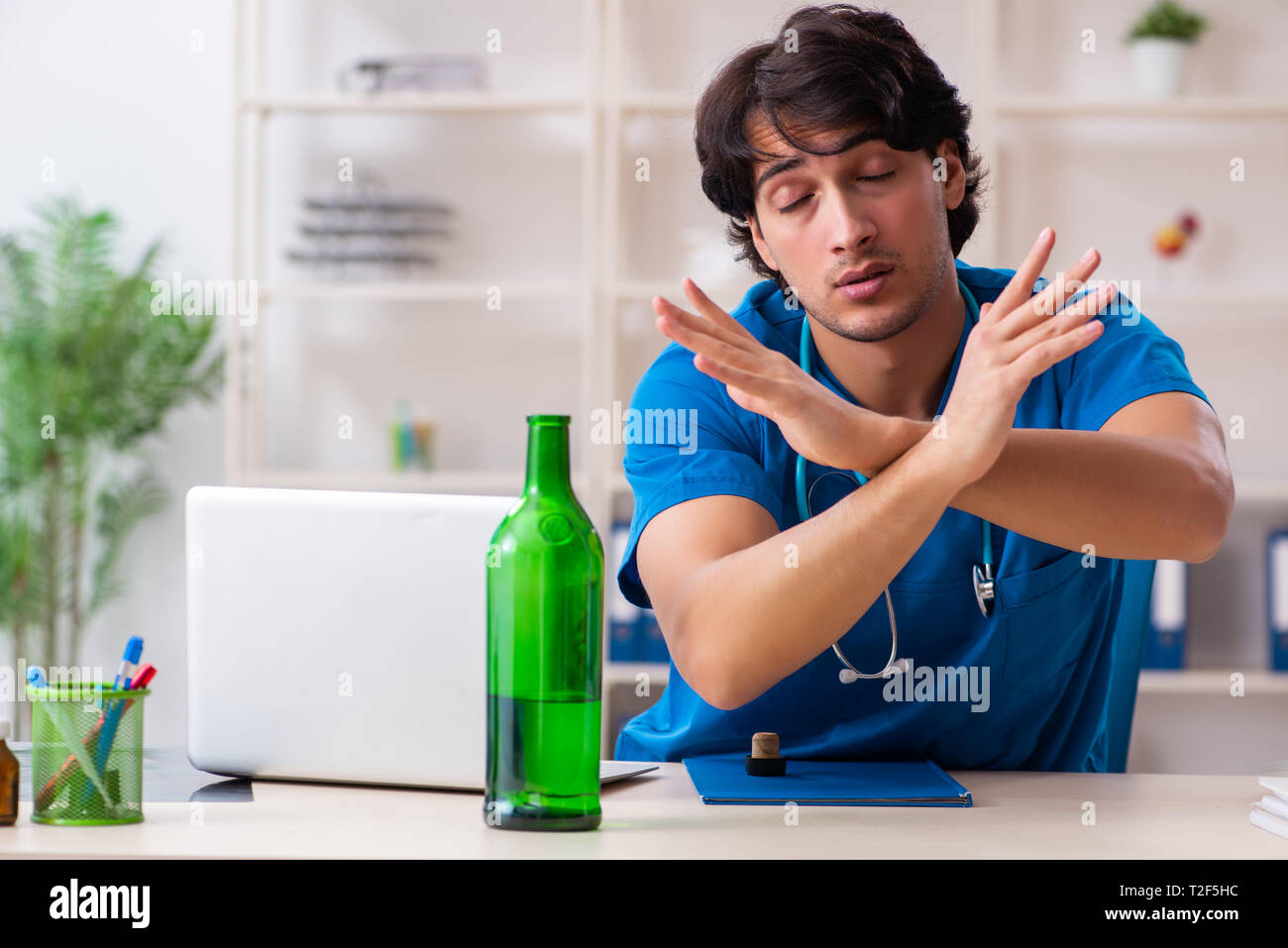 Young male doctor drinking in the office Stock Photo - Alamy