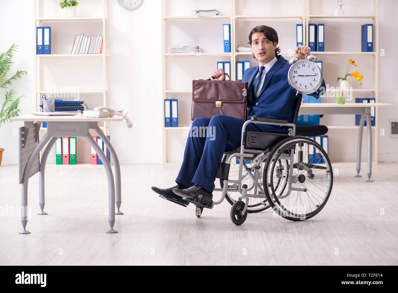 Young male employee in wheelchair working in the office Stock Photo - Alamy
