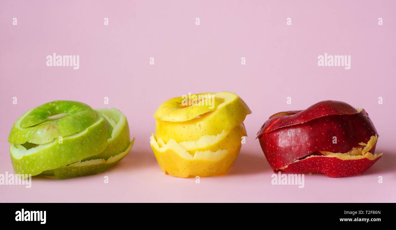 red, green, yellow apple peels on pink background as a symbol of ...