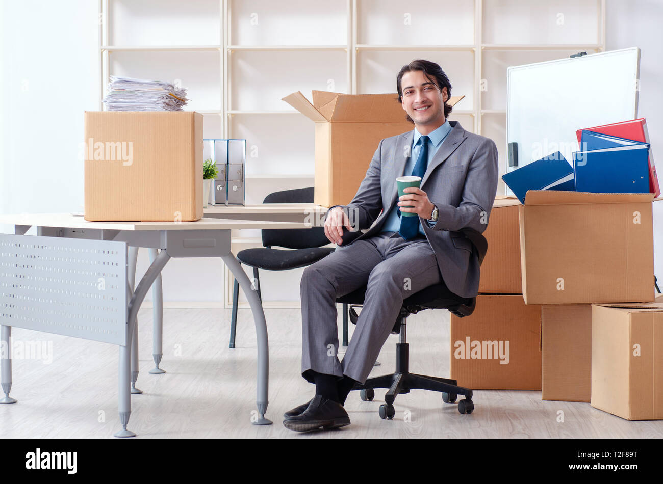 Young man employee with boxes in the office Stock Photo - Alamy