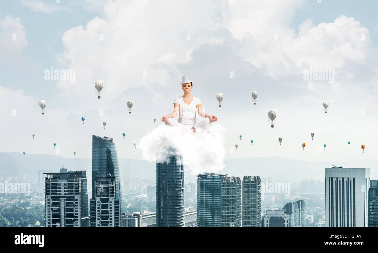 Woman in white clothing keeping eyes closed and looking concentrated ...