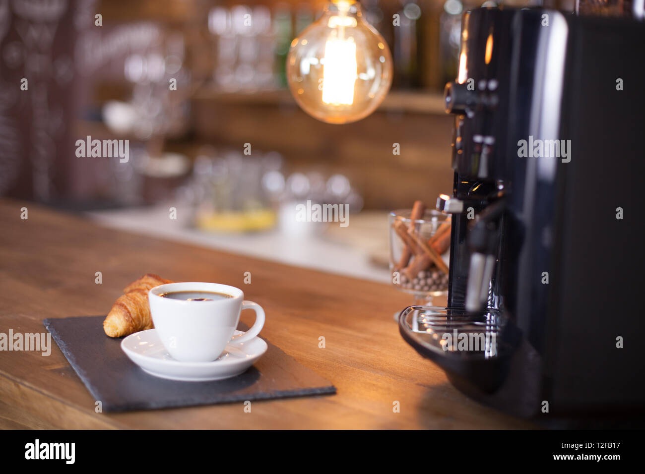 Cappuccino coffee cup next to black coffee machine. Vintage coffee shop ...