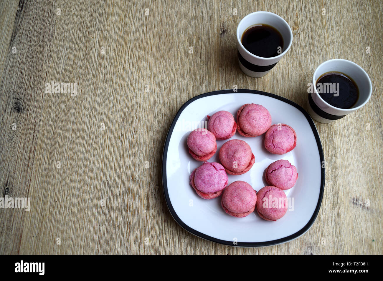 Coffee break with two cups of coffee and pink french macarons with ...