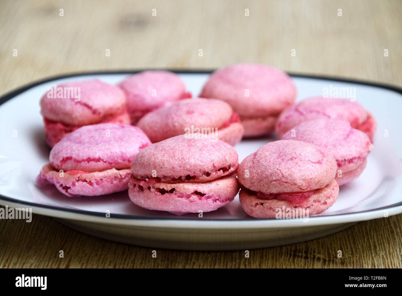 Pink french macarons with raspberry filling on a plate Stock Photo - Alamy