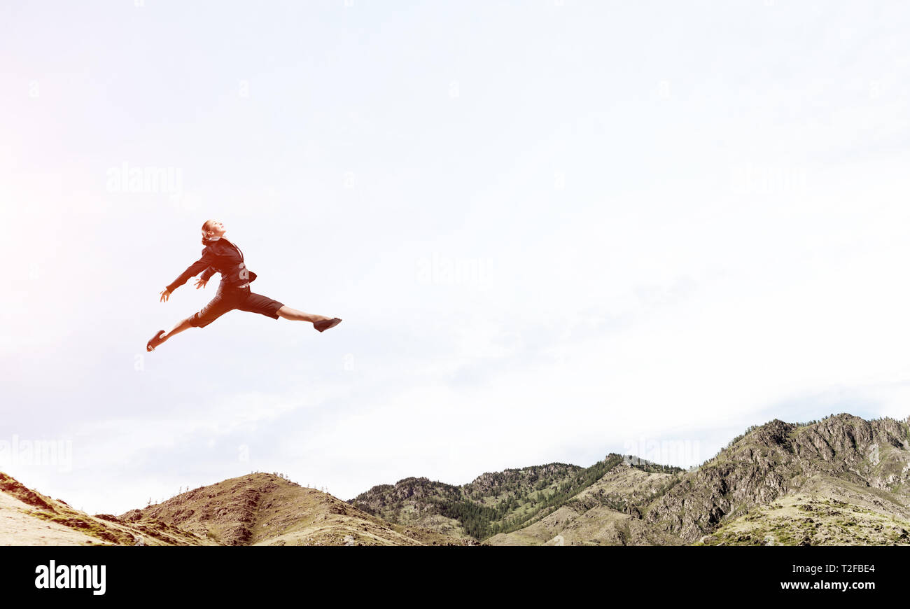 Attractive business woman in suit jumping in the air as symbol of ...