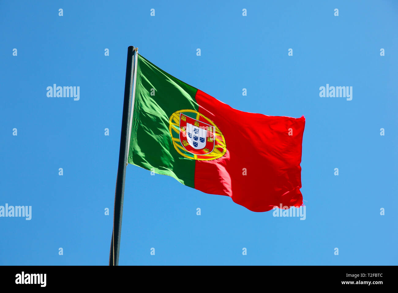 National Flag of Portugal blowing in the wind on flag pole with blue ...