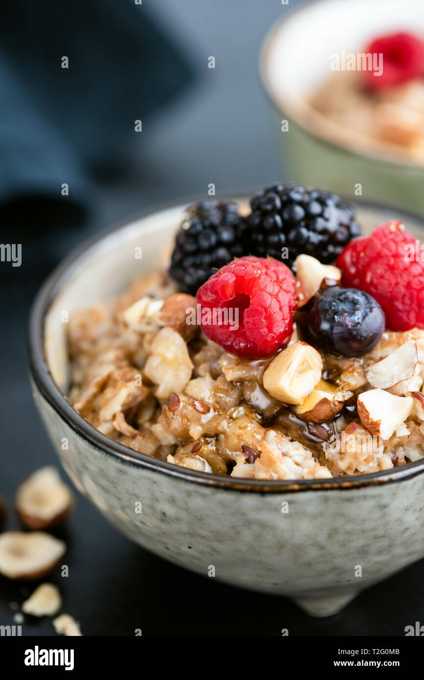 Oatmeal porridge with fresh summer berries, nuts and honey. Closeup ...