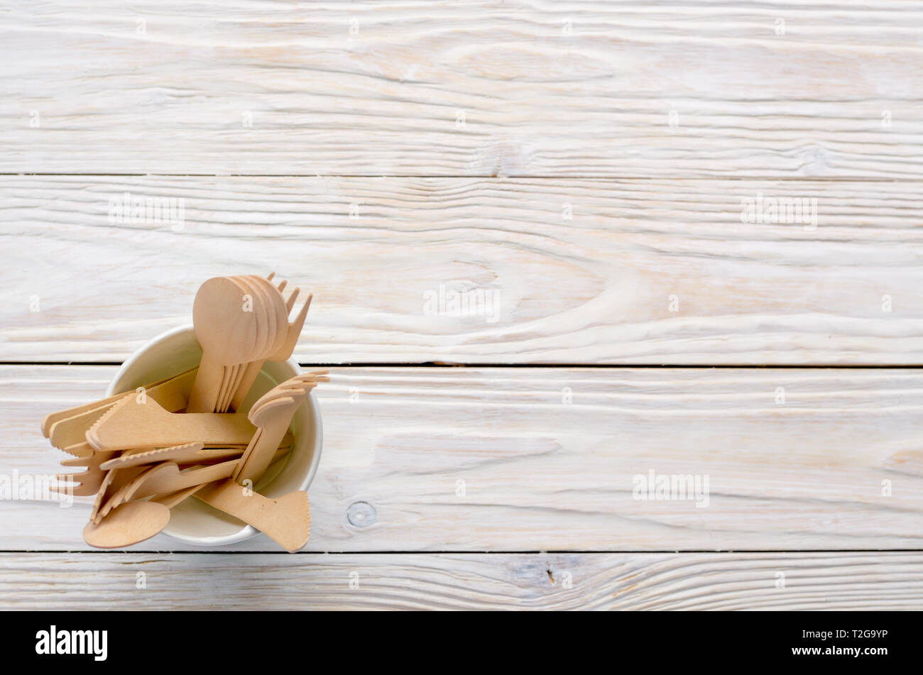 Wooden single use kitchenware in paper cup on white table. Top view ...