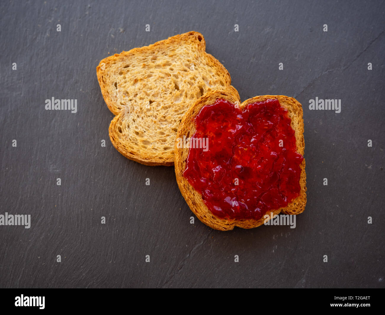 Two slices of toast with raspberry jam on a slate plate Stock Photo - Alamy