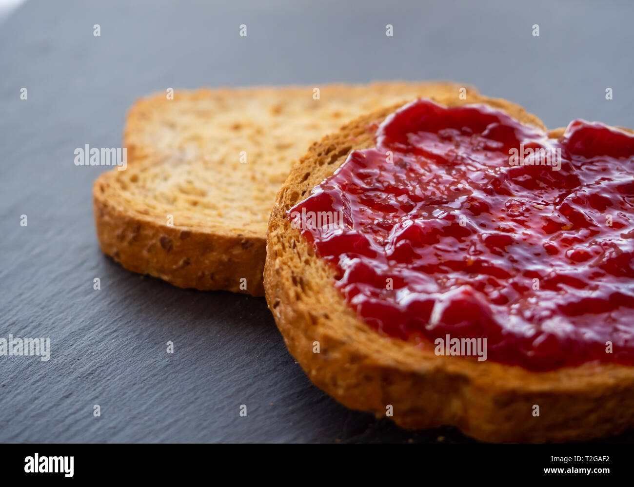 Two slices of toast with raspberry jam on a slate plate Stock Photo - Alamy