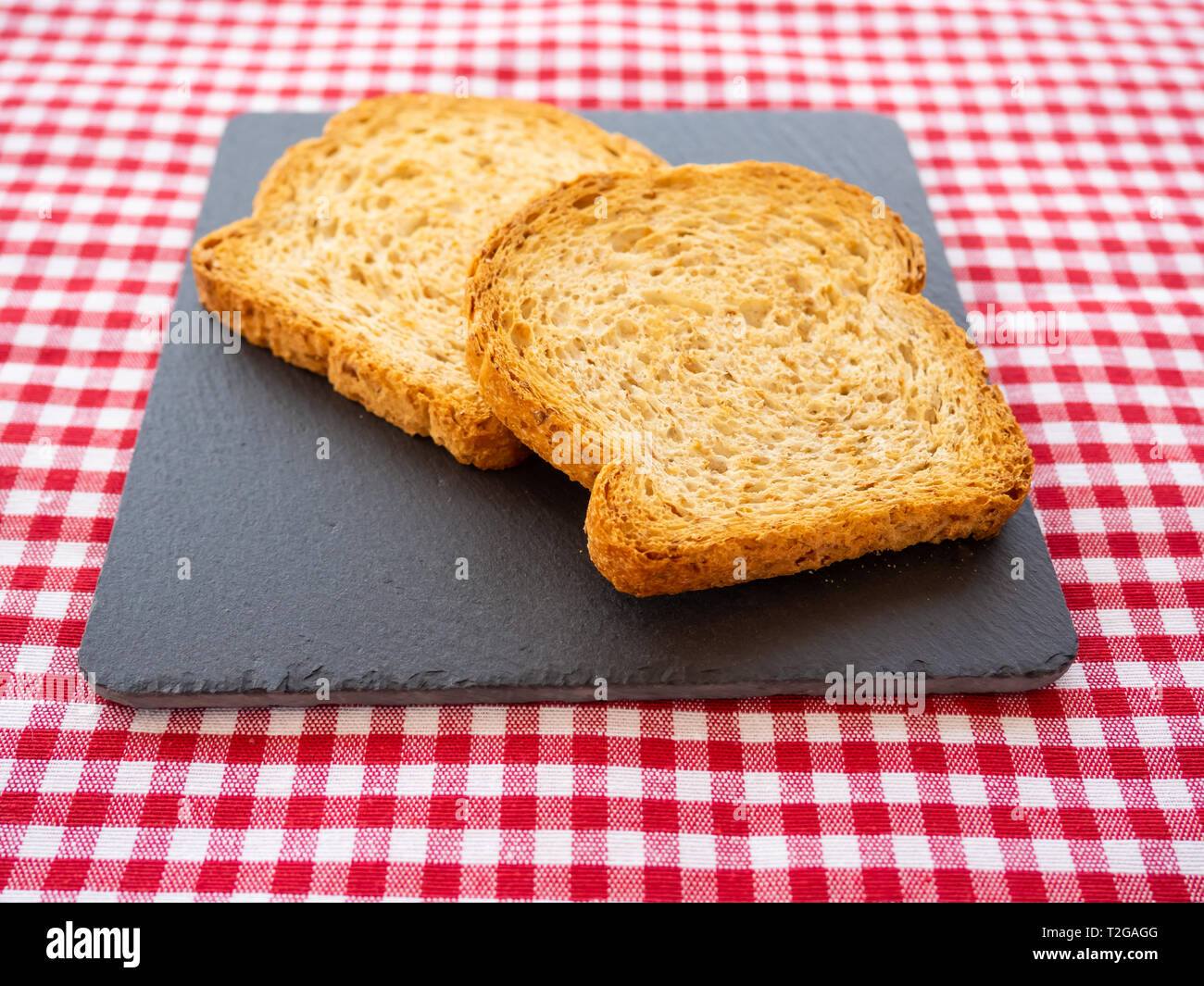 Two slices of toast on a slate plate and tablecloth vintage style Stock ...