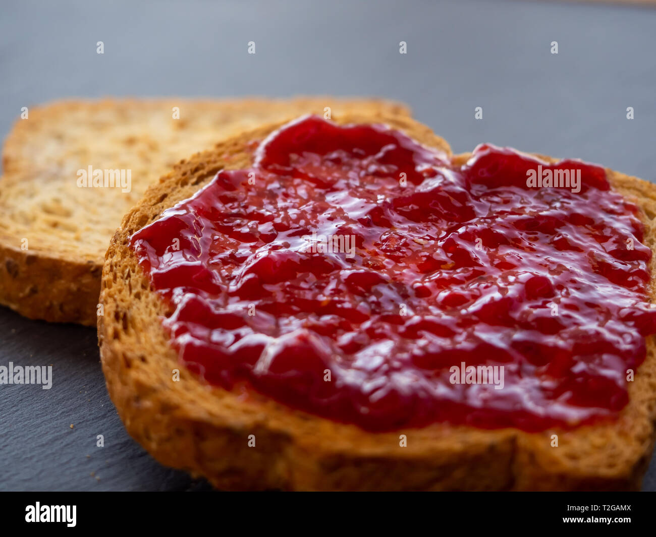 Two slices of toast with raspberry jam on a slate plate Stock Photo - Alamy