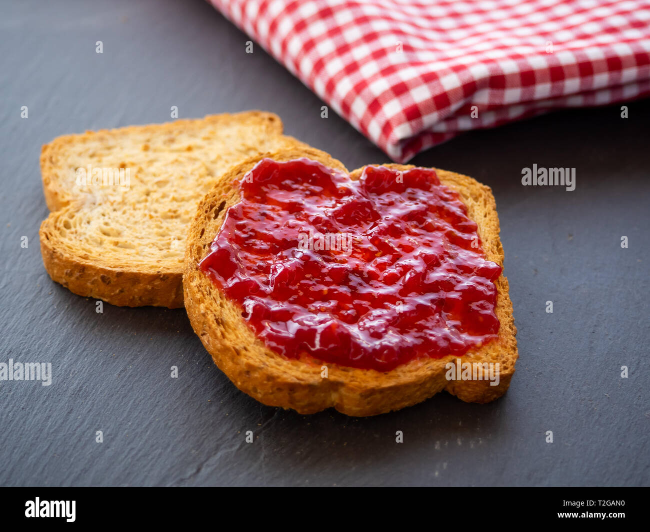 Two slices of toast with raspberry jam on a slate plate Stock Photo - Alamy