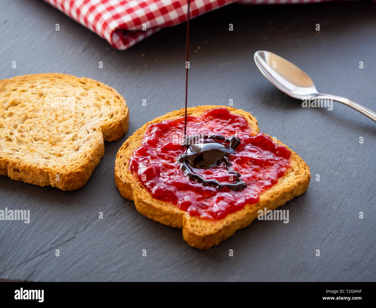 Pouring chocolate syrup on a slice of toast with raspberry jam Stock ...