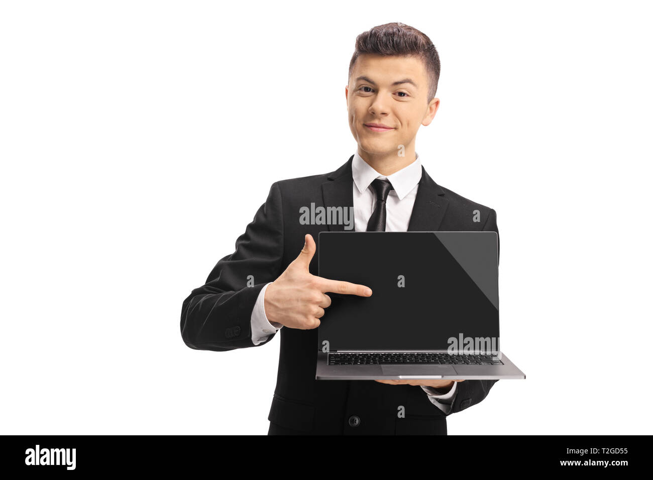 Smiling young guy in a suit pointing to a laptop isolated on white ...