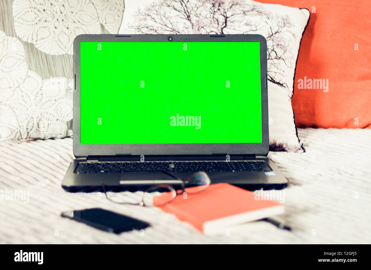 Green screen laptop, notebook, smartphone, glasses and pen on bad ...