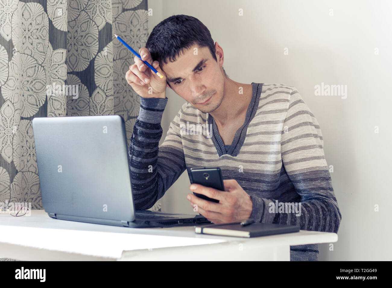 Portrait of young man In casual wear on the job working on laptop ...