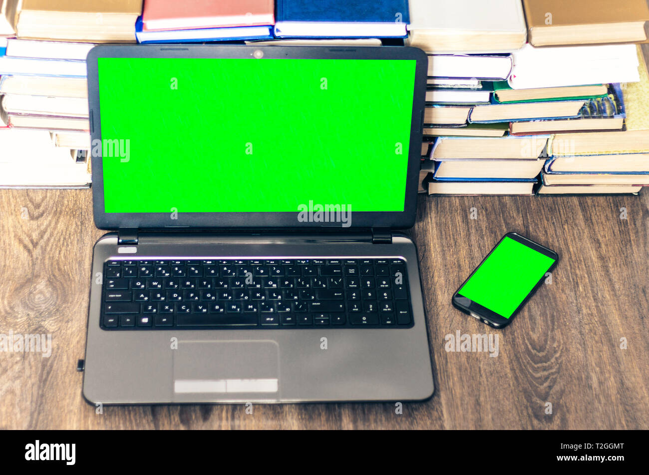 Green screen laptop, stack of books, smartphone, notebook and pencils ...