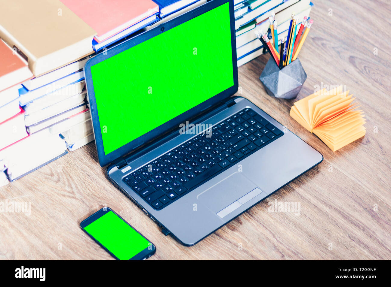 Green screen laptop, stack of books, smartphone, notebook and pencils ...