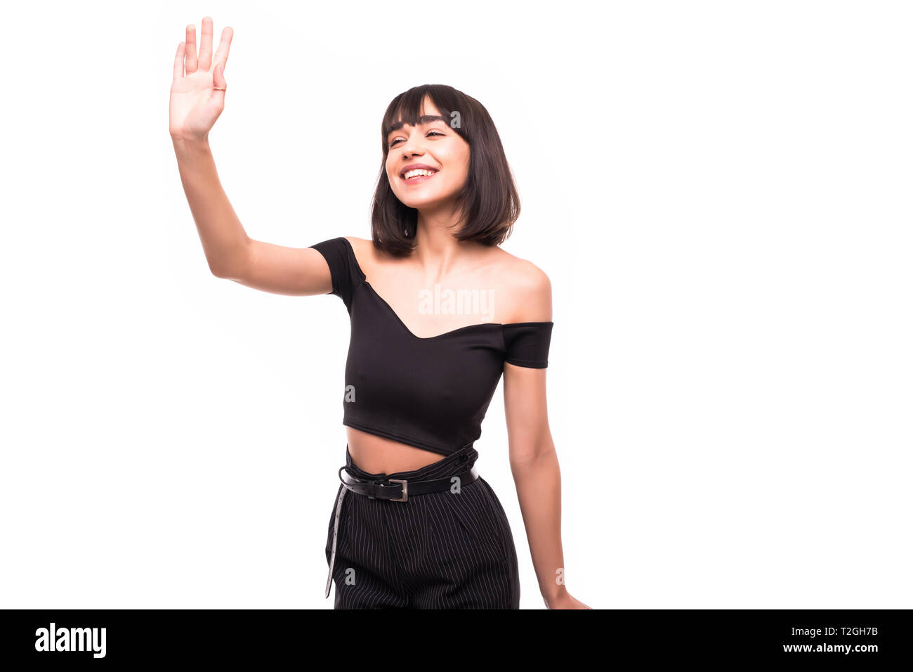 Full length portrait of a cheerful girl waving hand to camera isolated ...