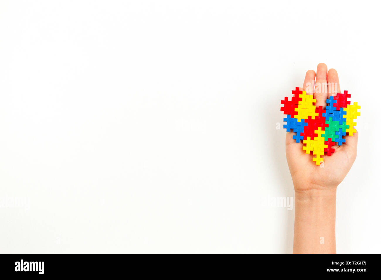 Colorful heart on kid hand over white background. World autism ...